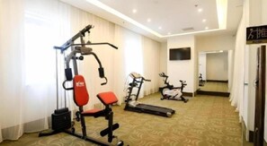 Quarto de hotel com área de ginásio, incluindo banco de musculação, bicicleta ergométrica e esteira.