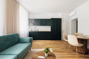 Uma sala de estar moderna com um sofá verde-água, uma mesa de jantar de madeira com cadeiras e uma cozinha com armários verde-escuro.
