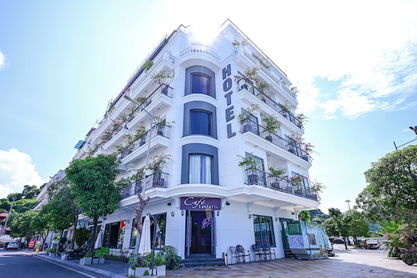 Hotel com vários andares, varandas, café e área externa para sentar.