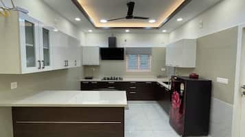 Cozinha moderna com armários brancos, uma ilha central e ventilador de teto.