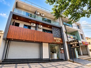 Um hotel moderno com estrutura em dois andares, fachada de vidro e uma placa indicando 'HOTEL A.D' com a inscrição 'QUARTOS DE LUXO' abaixo.