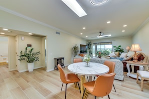 Uma sala de estar ampla com uma mesa de jantar, cadeiras laranja e um sofá.