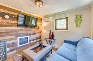 Uma sala de estar moderna com televisão de tela plana, lareira, sofá e um detalhe decorativo na parede.
