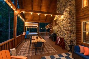 Um deck coberto ao ar livre com piso xadrez, uma banheira de hidromassagem e uma parede de pedra.