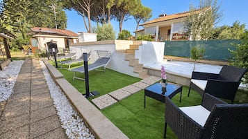 Área de pátio com mobiliário externo, uma piscina pequena e uma escadaria que leva a um deck coberto.