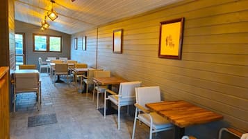 Restaurante com paredes e mesas de madeira, apresentando obras de arte emolduradas nas paredes.