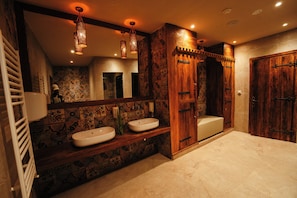 Casa de banho com duas pias, espelho e porta de madeira.