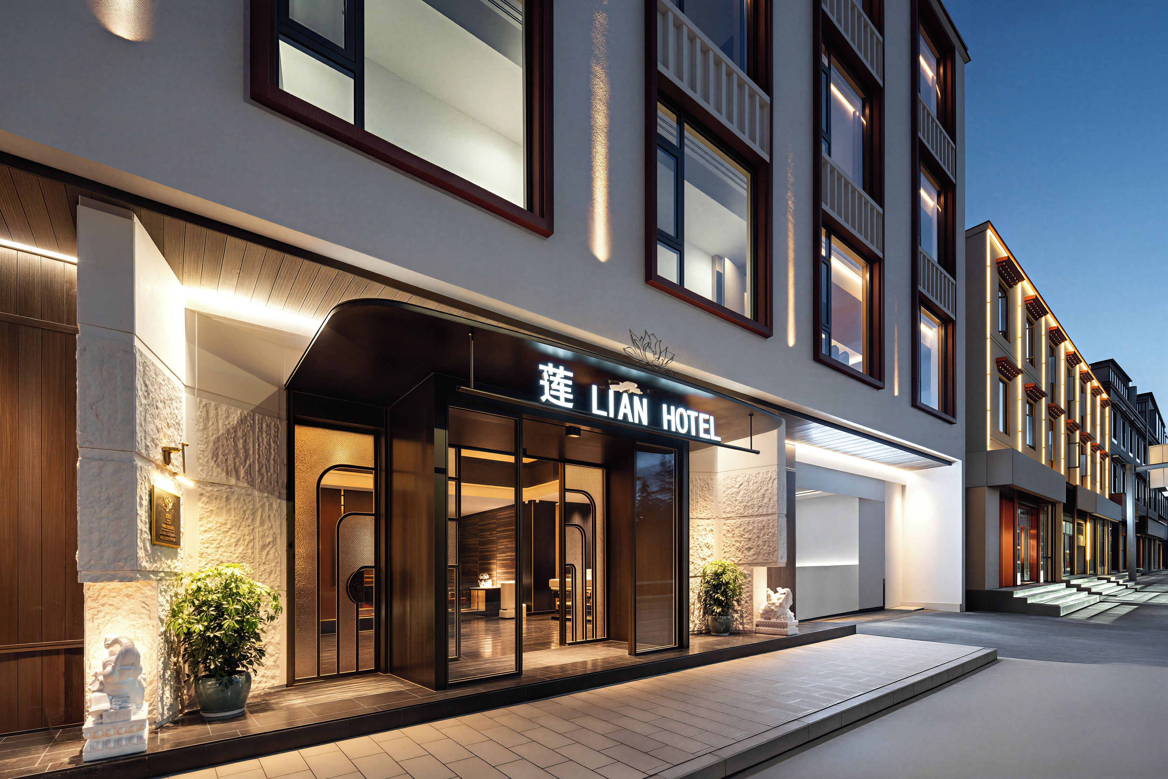 Entrada de hotel com fachada moderna, grandes portas de vidro e uma placa com a inscrição 'LIAN HOTEL'.