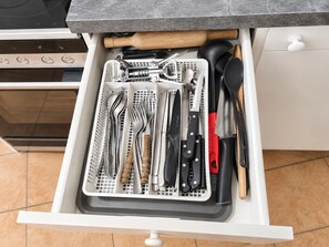 Uma gaveta de cozinha com utensílios e panelas.