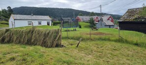 Paisagem rural com casas, fardos de feno e um campo gramado.