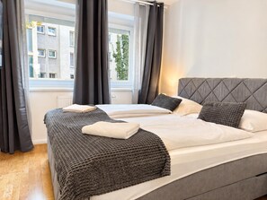 Quarto de hotel com cama, cortinas e janela com vista para edifícios.