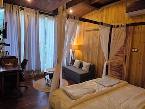 Quarto com uma cama, escrivaninha, poltrona, sofá e abajur.