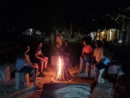 Um grupo de pessoas reunido ao redor de uma fogueira à noite.