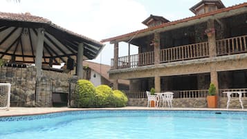 Piscina com um edifício de fachada em pedra ao fundo.