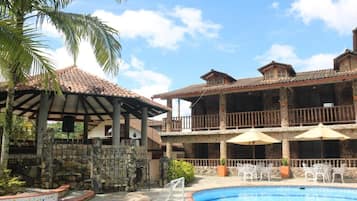 Hotel com piscina, área de estar externa e varanda coberta.