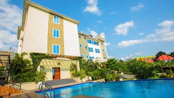 Hotel com piscina, vários andares e área de jardim.