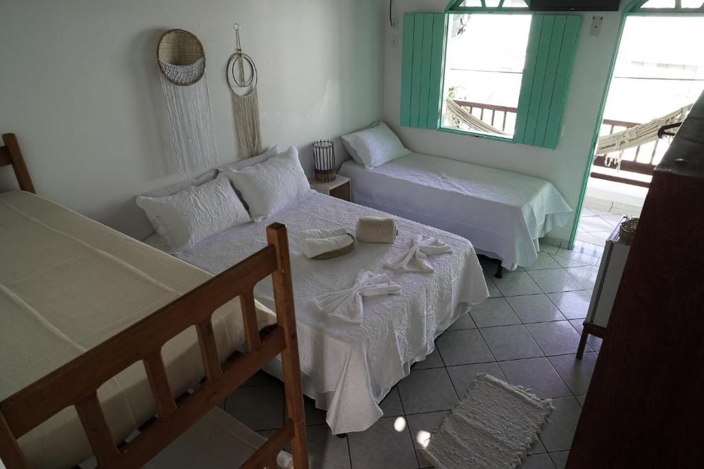 Quarto com duas camas, uma mesa de madeira e uma rede.