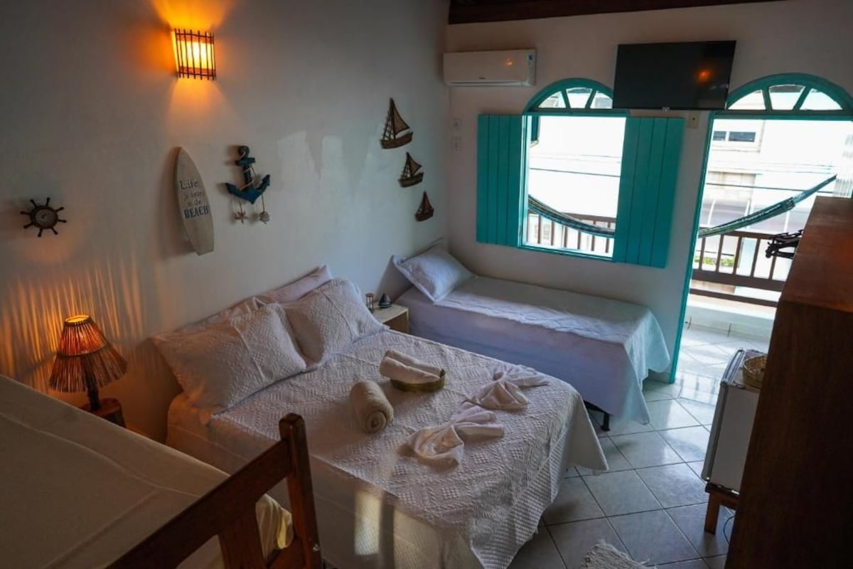 Quarto de hotel com duas camas, uma rede e decoração náutica.