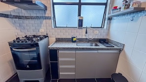 Uma cozinha compacta com fogão a gás, pia e janela.