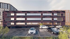 Um edifício com vários andares e um estacionamento em frente.