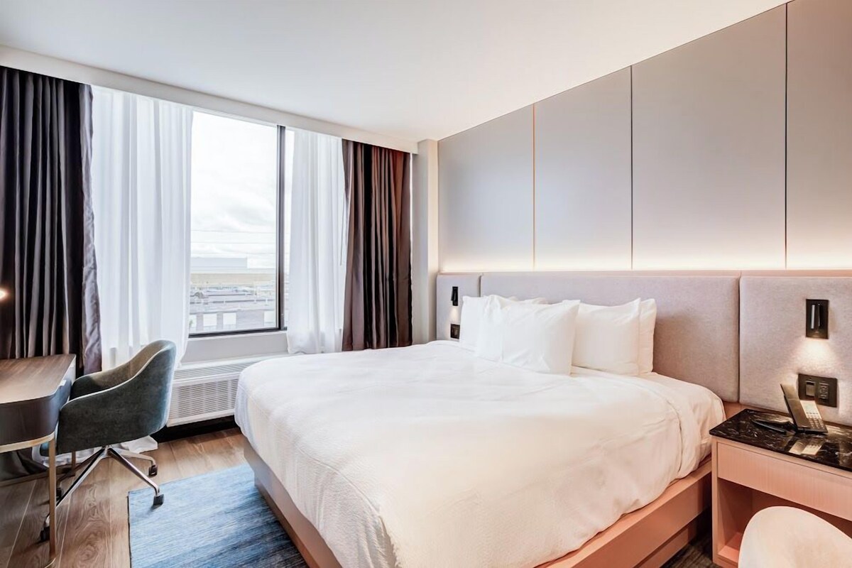 Quarto de hotel com uma cama grande, uma escrivaninha e uma cadeira.
