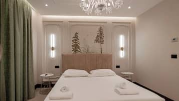 Quarto de hotel com uma cama grande, duas mesas de cabeceira, um candelabro e uma parede com um mural de tema natural.