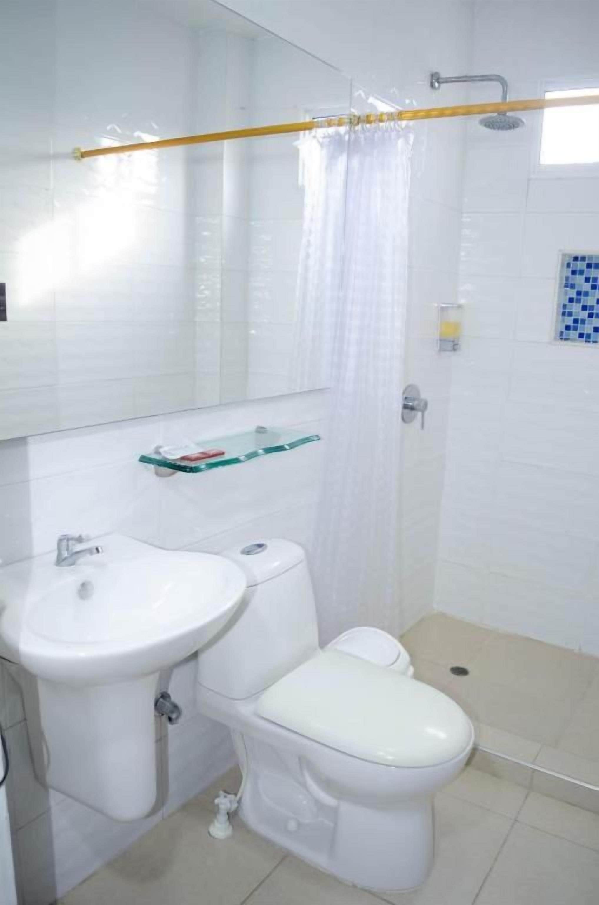 Casa de banho com lavatório branco, sanita e zona de duche.