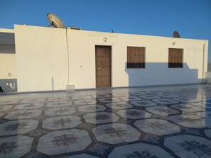 Um edifício com telhado plano, uma porta e duas janelas com persianas.