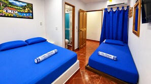Quarto de hotel com duas camas, banheiro e um quadro na parede.