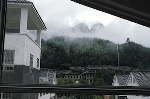 Vista de um edifício com telhado tradicional e montanha ao fundo.