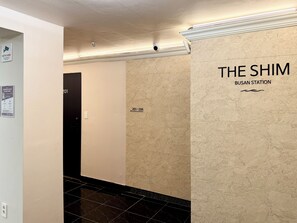Um corredor com uma placa indicando 'THE SHIM BUSAN STATION' e portas numeradas.