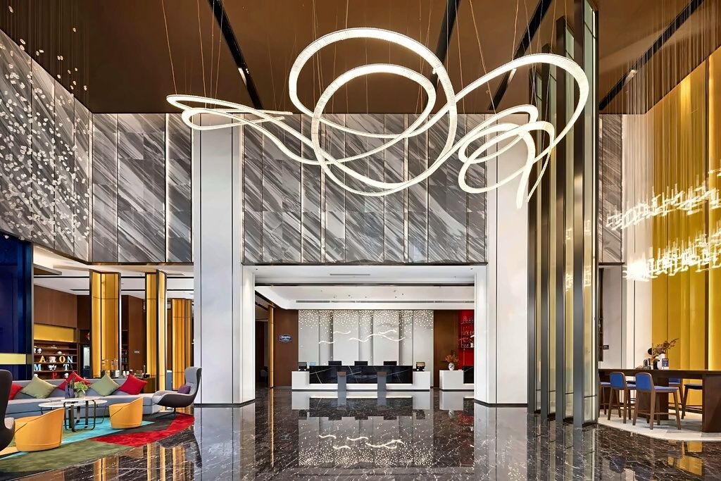 Um lobby moderno com piso de mármore, balcão de recepção e áreas de estar.