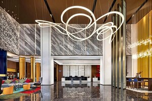 Um lobby moderno com piso de mármore, balcão de recepção e áreas de estar.