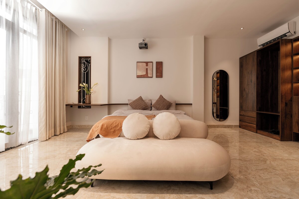 Quarto moderno com cama grande, mesa de cabeceira, espelho e guarda-roupa.
