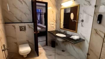 Um banheiro moderno com piso de mármore, box de vidro, vaso sanitário branco e toucador com espelho.