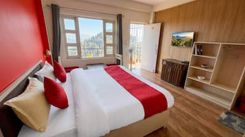 Quarto de hotel com cama, televisão, guarda-roupa e varanda com vista.