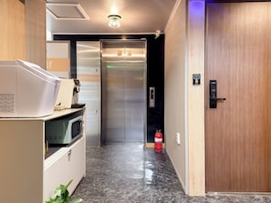 Corredor de hotel com uma máquina de café, extintor de incêndio e elevador.