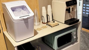 Uma cozinha compacta com cafeteira, micro-ondas e pequena geladeira.