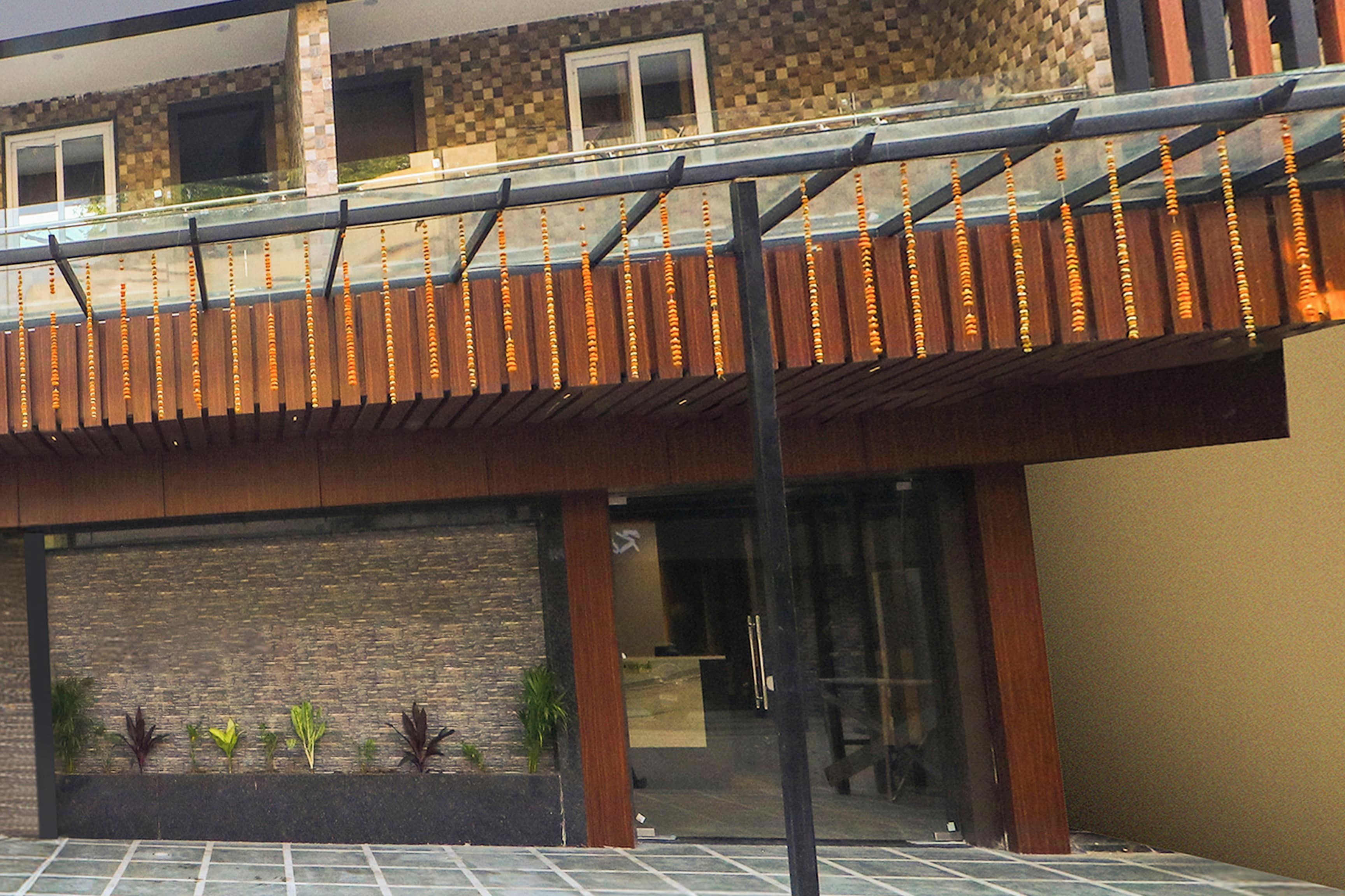 Um edifício moderno com varanda, entrada por porta de vidro e parede de pedra com plantas.