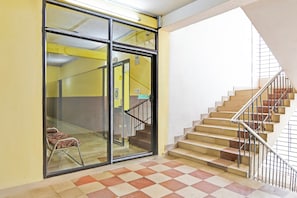 Escadaria com corrimão de metal, piso estampado e porta de vidro com um aviso.