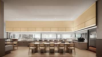 Cozinha moderna com ilha central, eletrodomésticos embutidos e área de refeições com cadeiras.