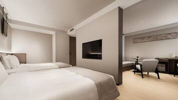 Quarto de hotel moderno com cama grande, escrivaninha e televisão de tela plana na parede.