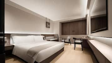 Quarto de hotel moderno com uma cama grande, uma escrivaninha, uma cadeira e um sofá.