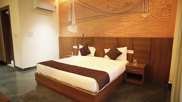 Quarto de hotel com cama grande, cabeceira de madeira, mesa de cabeceira e um mural na parede com a imagem de uma ponte.