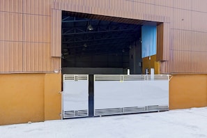 Um grande edifício industrial com fachada de metal e uma grande porta aberta.