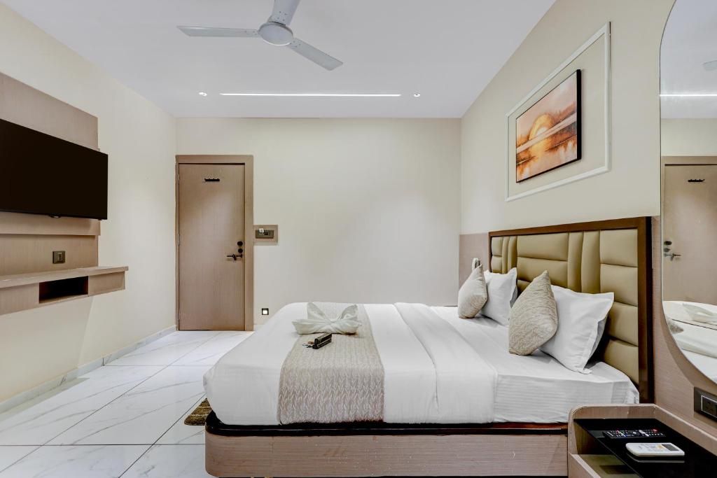 Quarto de hotel com cama, televisão de tela plana, ventoinha no teto, pintura na parede e cabeceira de madeira.