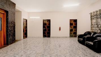 Quarto amplo com piso de mármore, sofá de couro preto e duas portas com painéis de vidro decorativos.
