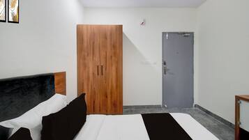 Quarto de hotel com cama, guarda-roupa e porta.