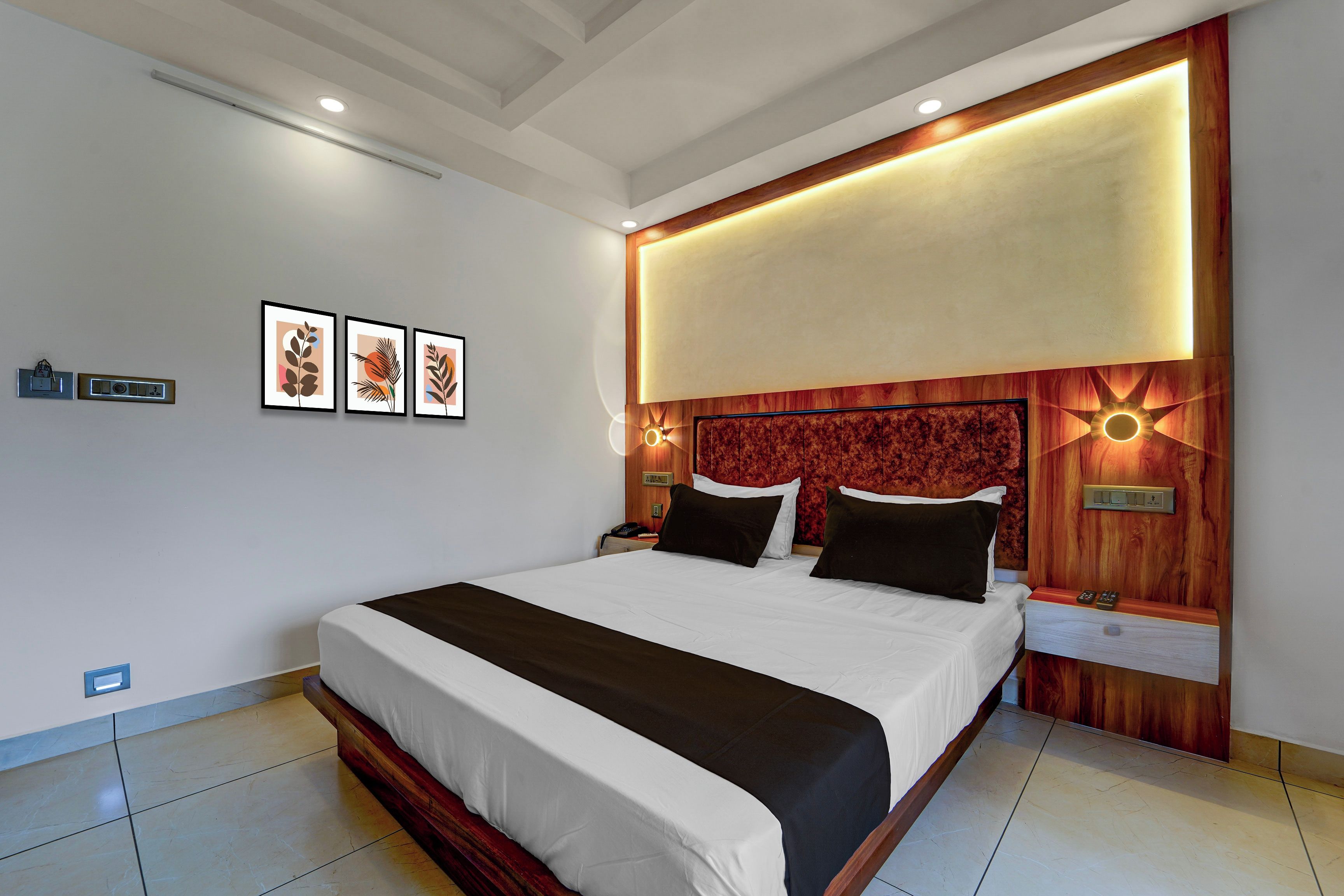 Quarto de hotel moderno com uma cama grande, cabeceira de madeira e luminária fixada na parede.
