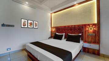 Quarto de hotel moderno com uma cama grande, cabeceira de madeira e luminária fixada na parede.